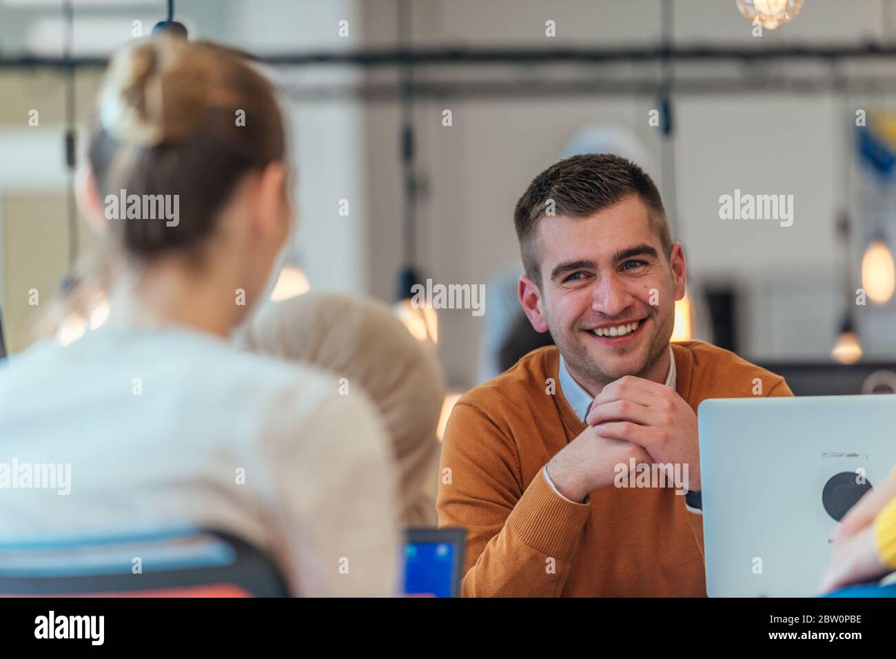 Young business colleagues talking to each other while leaning on a desk ...