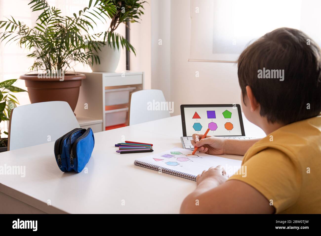 Student boy performs his academic tasks and learns from home through ...