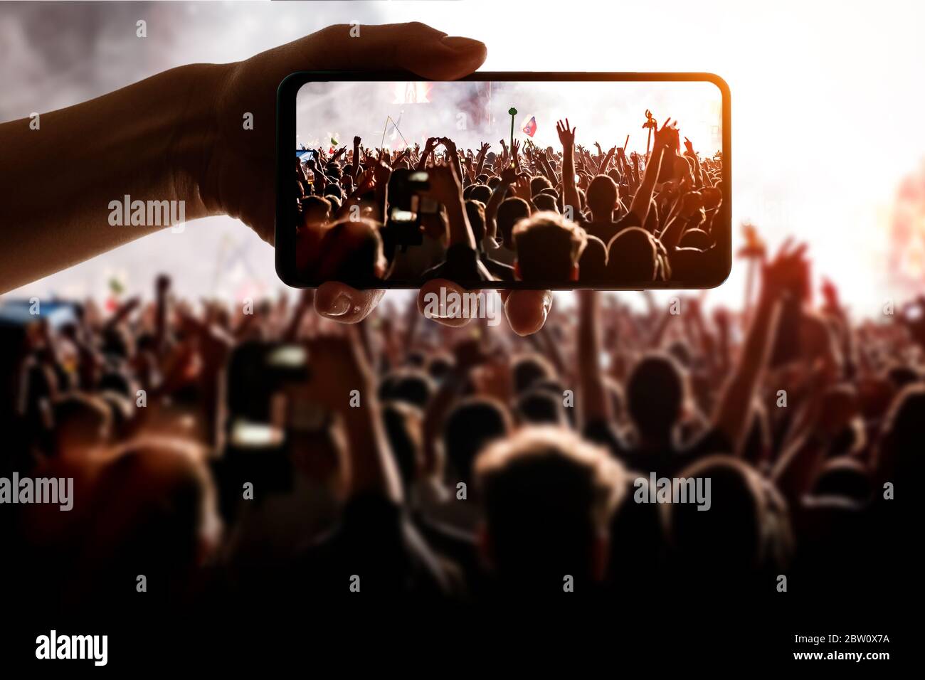 Hand with smartphone records live music concert. Using a mobile phone ...