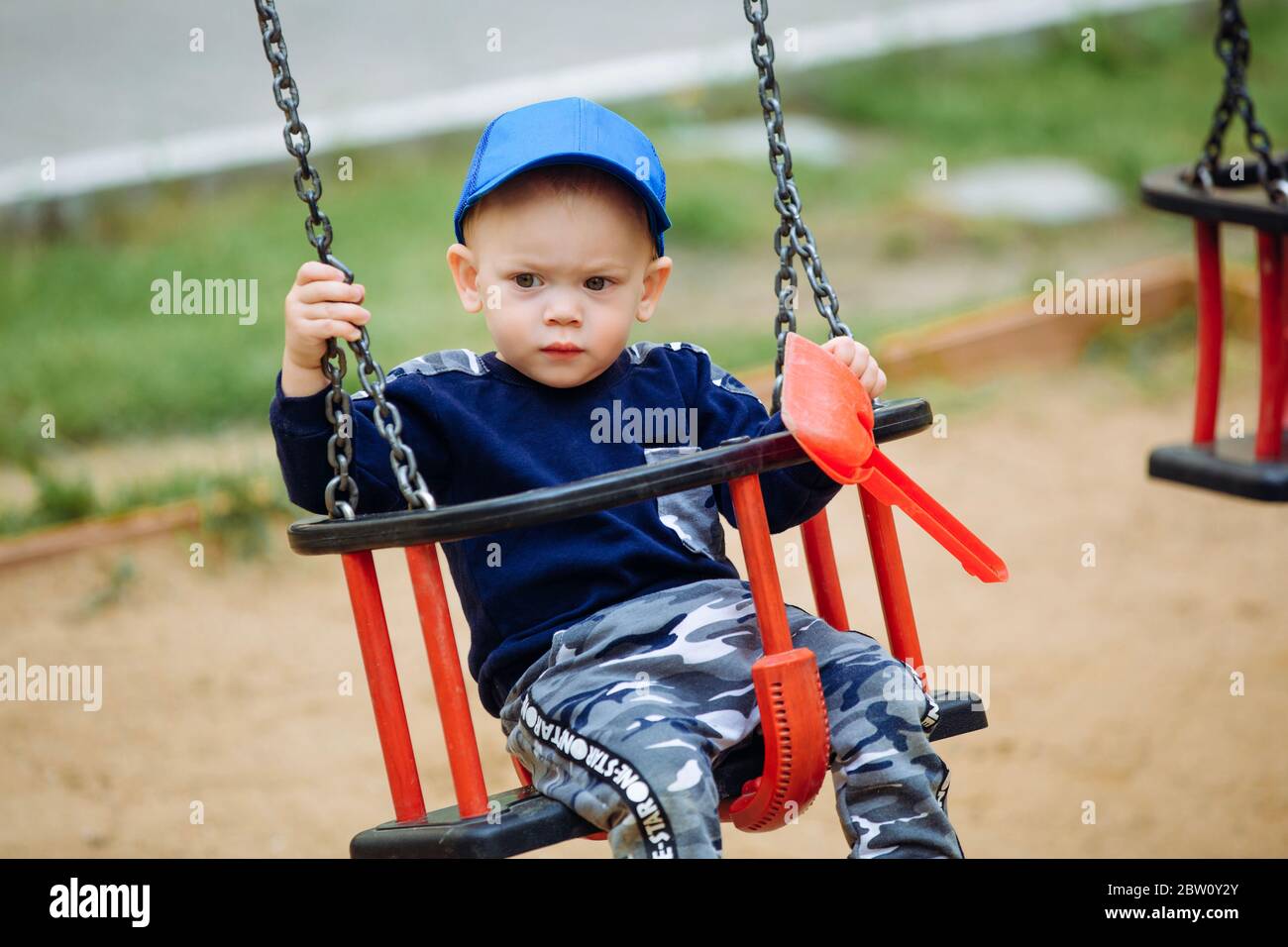 A Boy 1-2 years old riding a swing and holding toys in his hands Stock ...