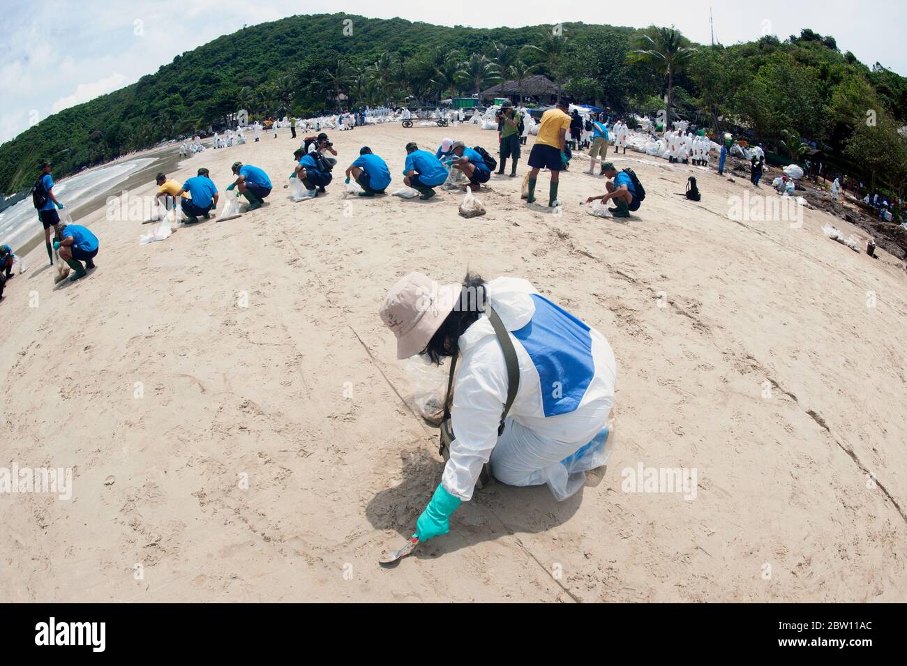 Workers and volunteers are shoveling sand with crude oil contaminated ...