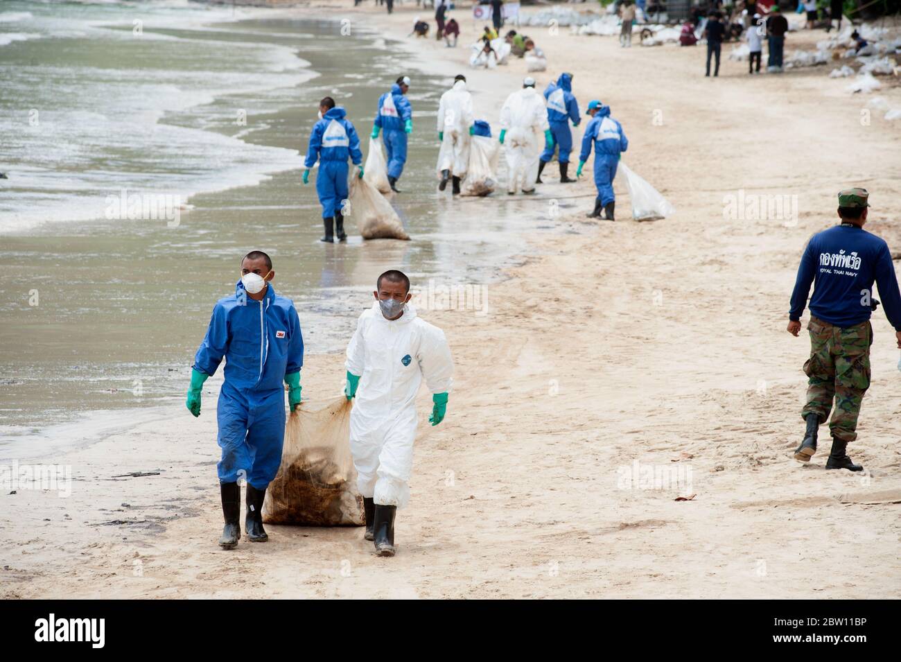 Workers and volunteers are shoveling sand with crude oil contaminated ...