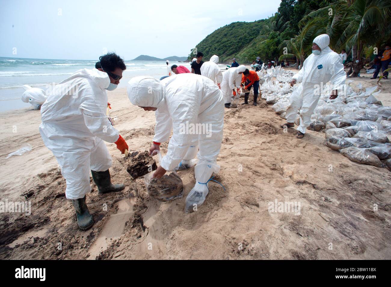 Workers and volunteers are shoveling sand with crude oil contaminated ...