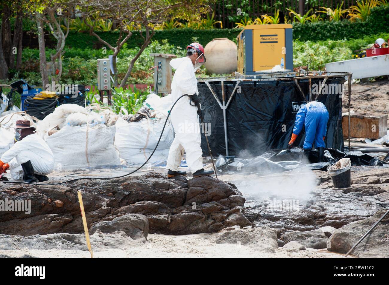 Workers and volunteers are spraying chemicals onto crude oil ...