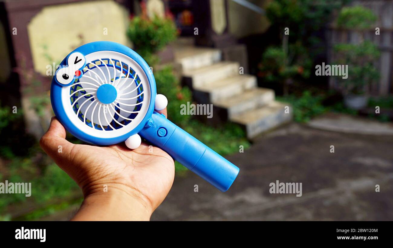 Close up hand holding a portable fan Stock Photo - Alamy
