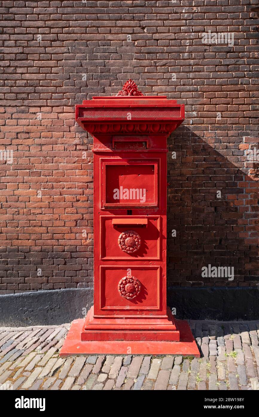 red old Dutch mailbox standing against a brick wall Stock Photo - Alamy