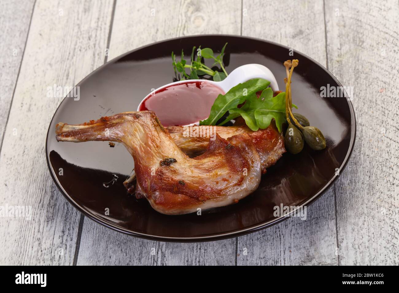 Roasted rabbit legs with cowberry sauce Stock Photo - Alamy