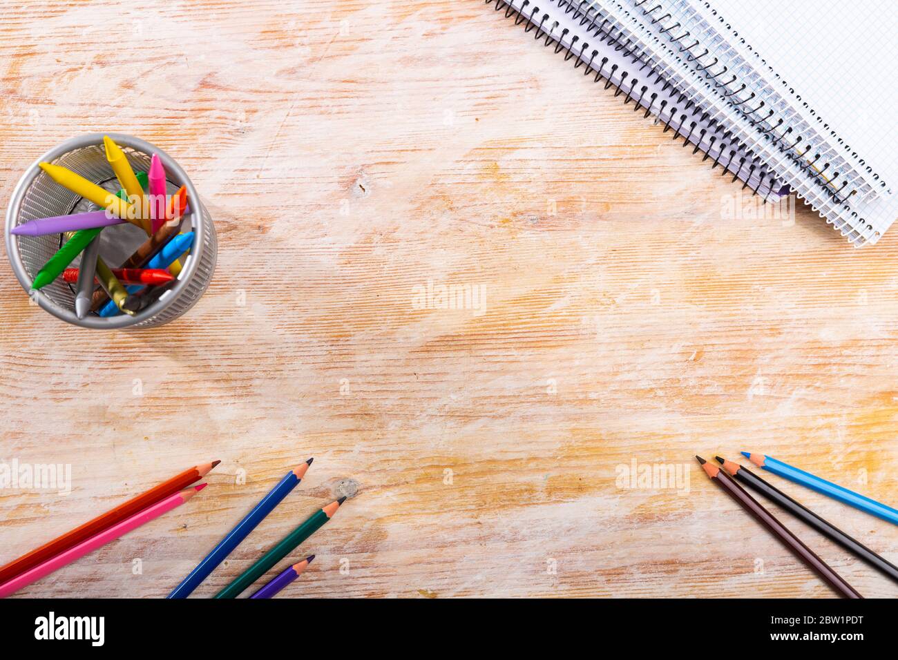 Colored pencils and workbooks on wooden student desk with place for ...