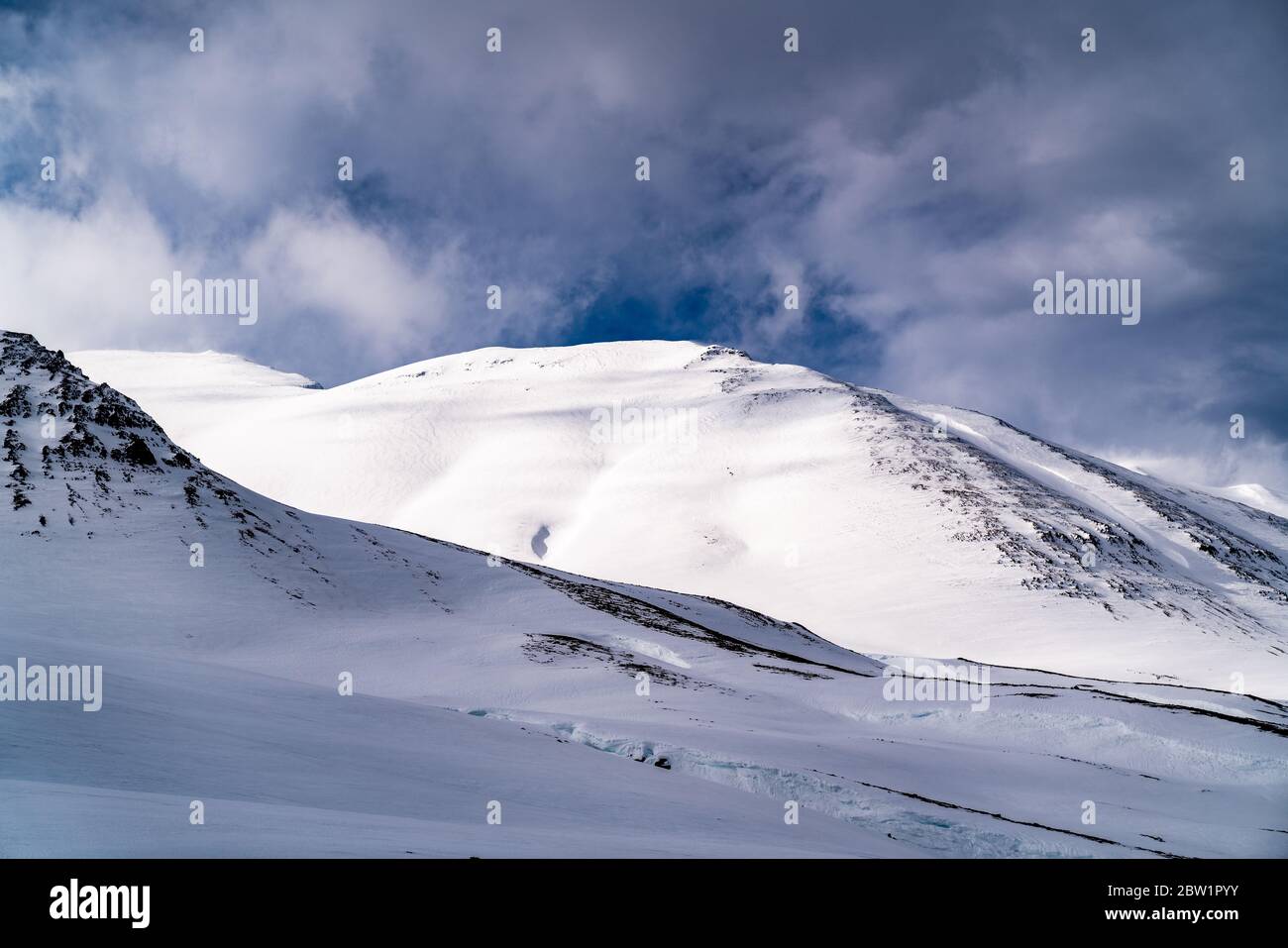The sun hitting a smooth surfaced mountain while partly covered by a ...