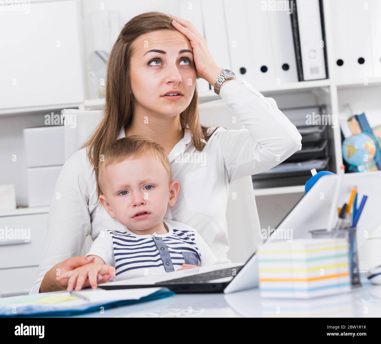 Perplexed female with kid is having problems while working in office ...