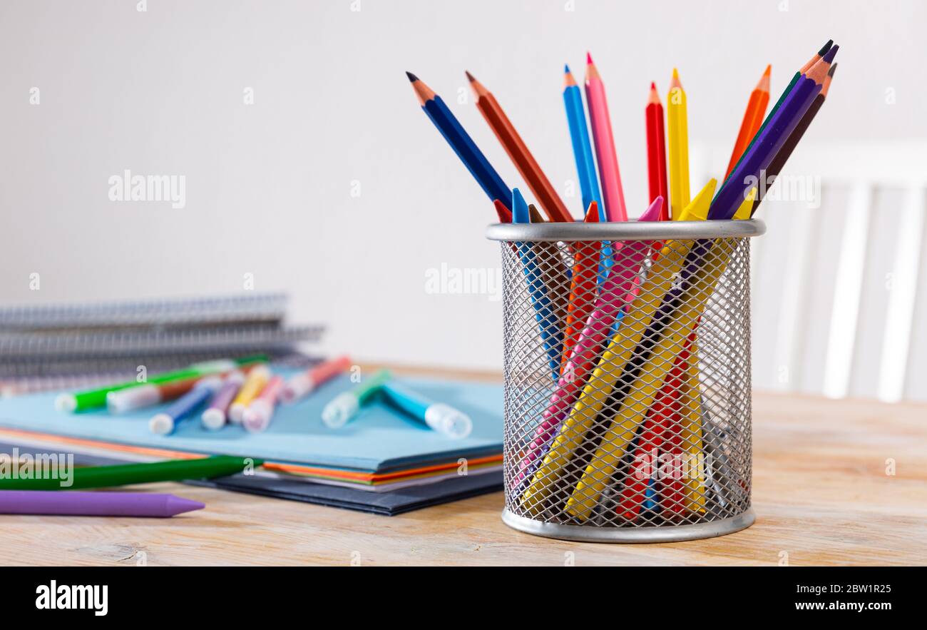 Closeup of pencils and wax pastel with papers and workbooks on desk in ...