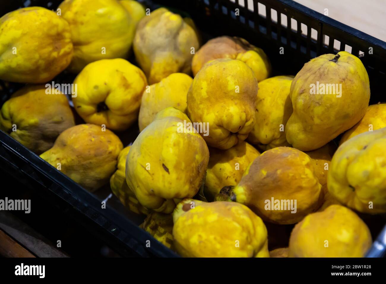 Fresh yellow quince in plastic box on market showcase. Organic vitamin ...