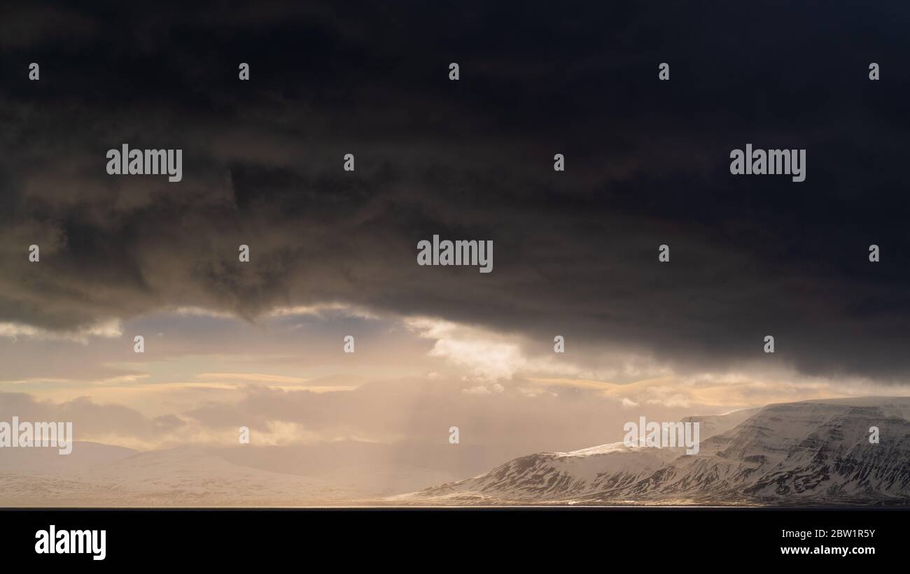 Sun rays shining through the dark clouds after a storm illuminating the ...