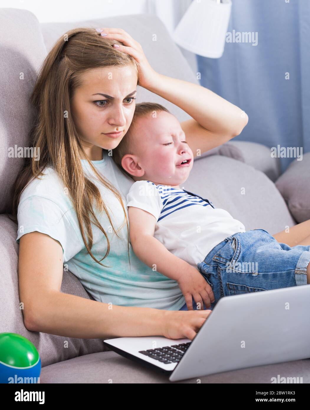 Perplexed girl is having issue with work while child crying at home ...