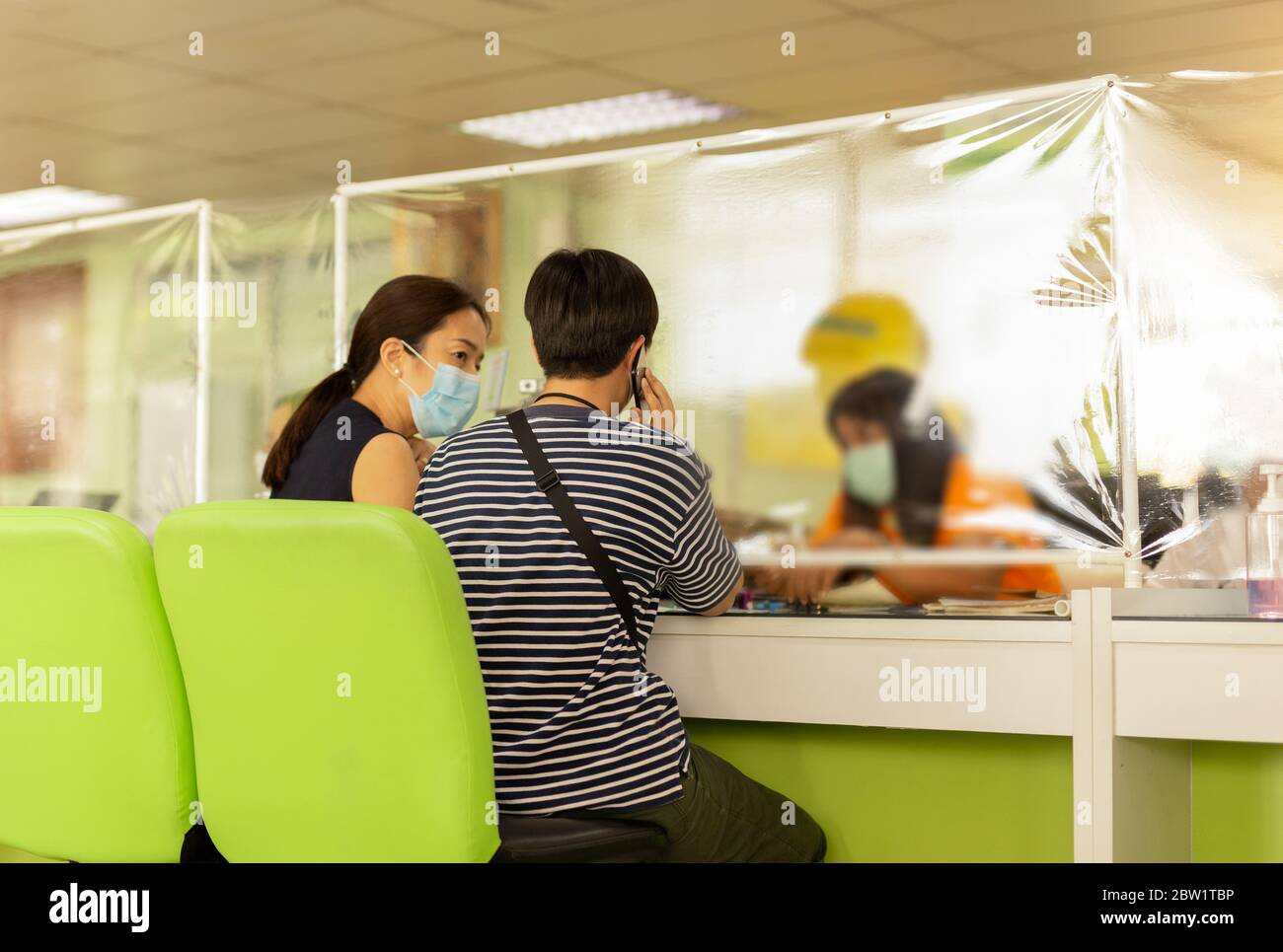 Customer with mask at counter service with staff behind Plastic ...