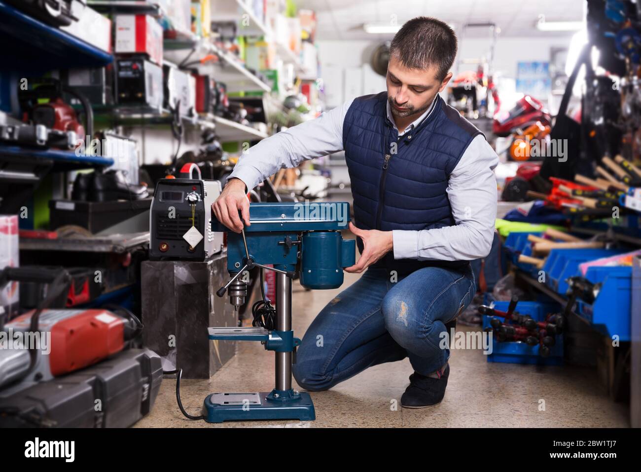 Positive man is choosing new puncher in tools shop Stock Photo - Alamy