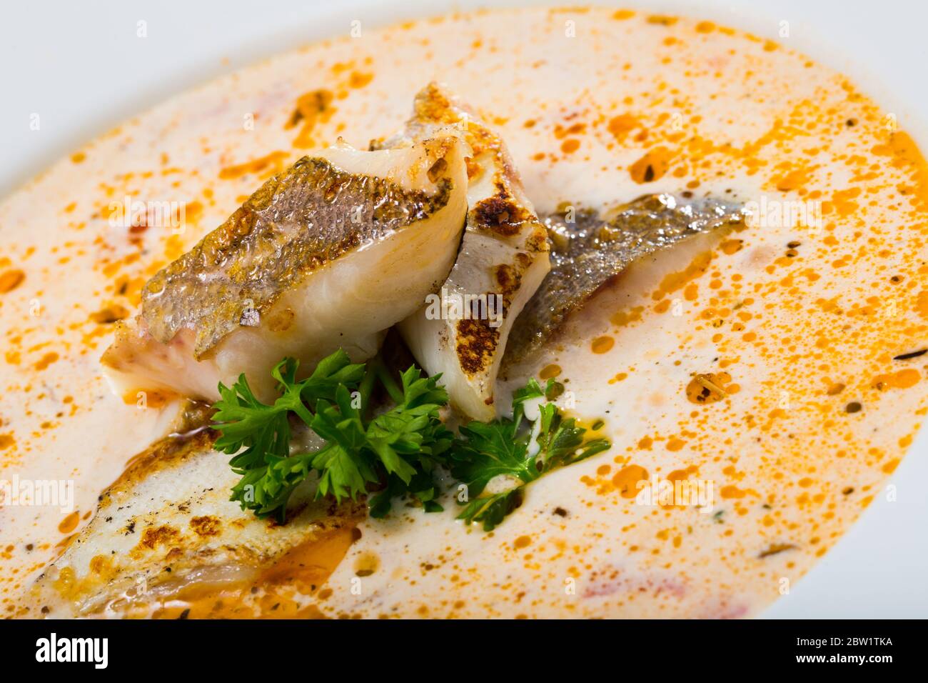 Image of tasty creamy soup with white fish pollock and greens at plate ...