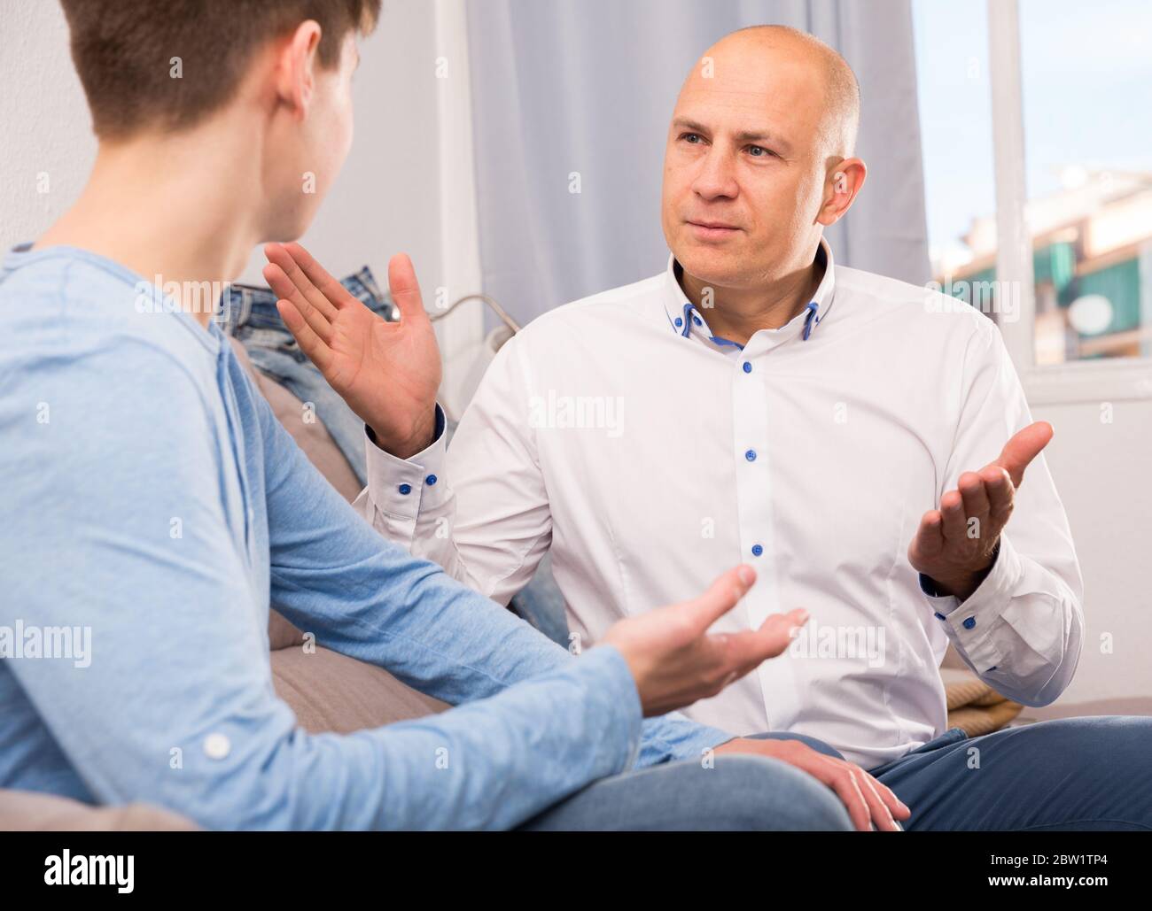 Portrait of father talking to teenage son, having friendly conversation ...