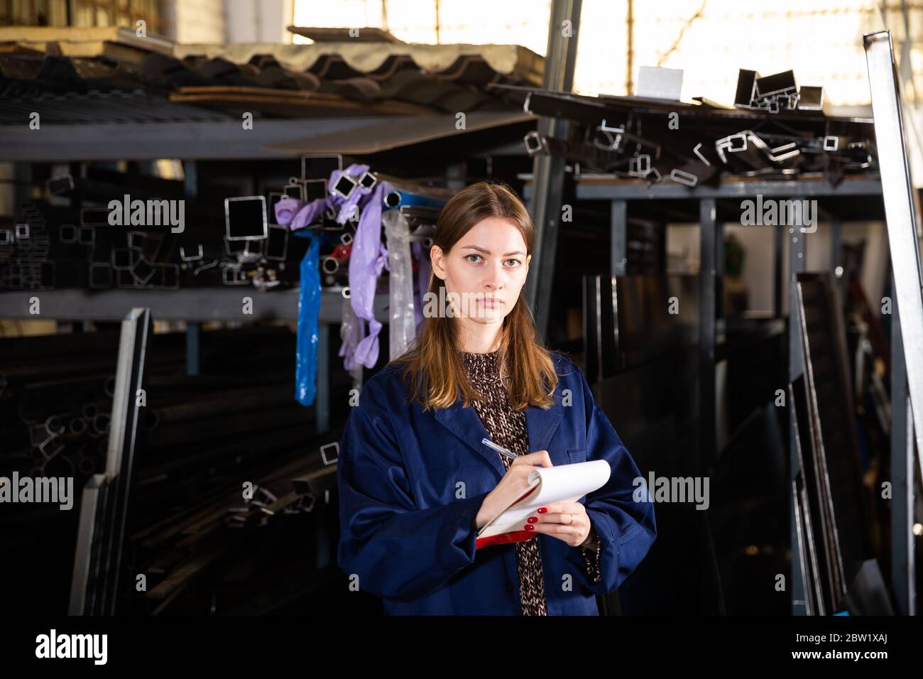 Young female standing with notepad in production workshop Stock Photo ...