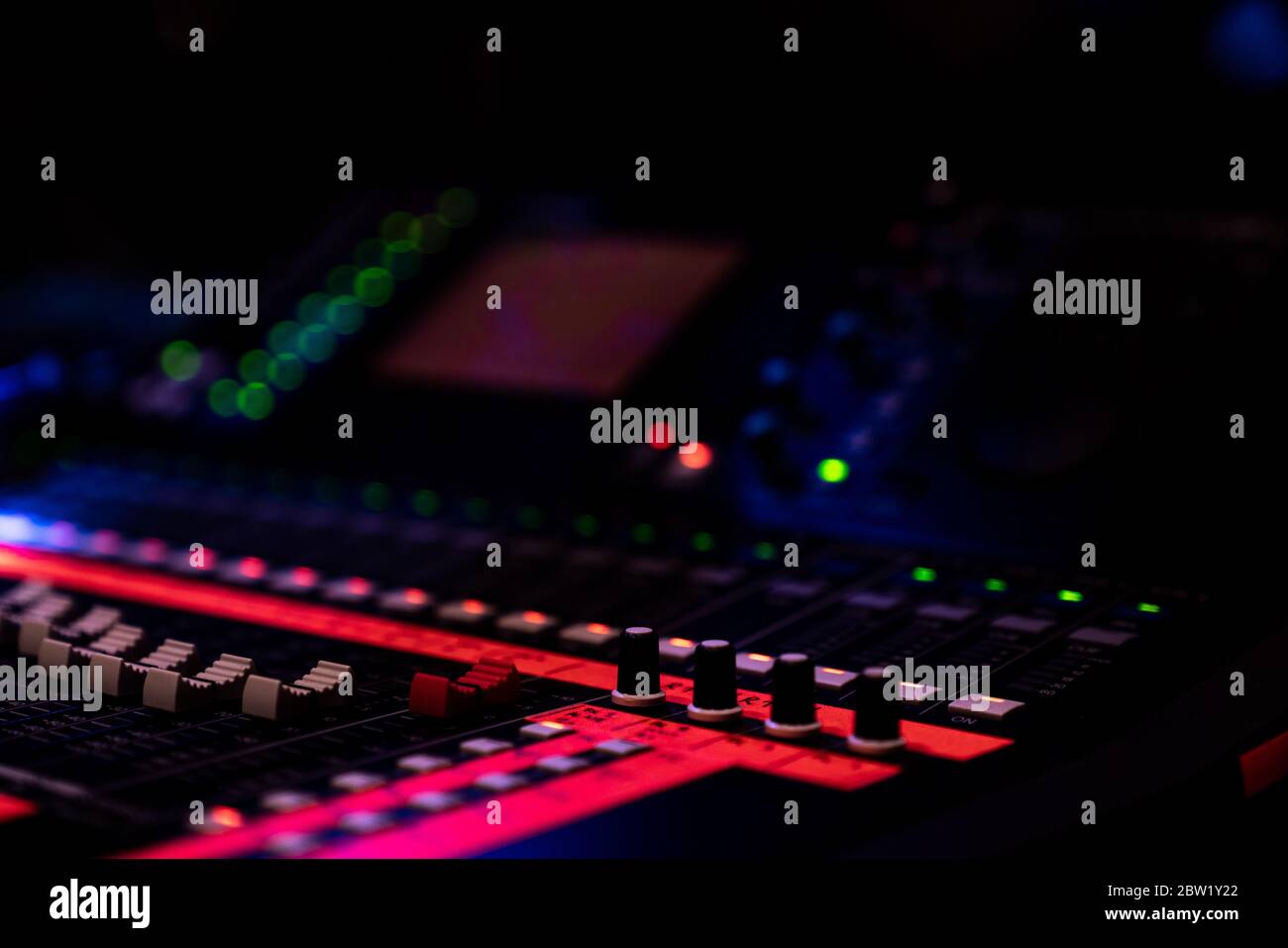 Audio mixing console with colourful tape markings in dim lightning in a ...