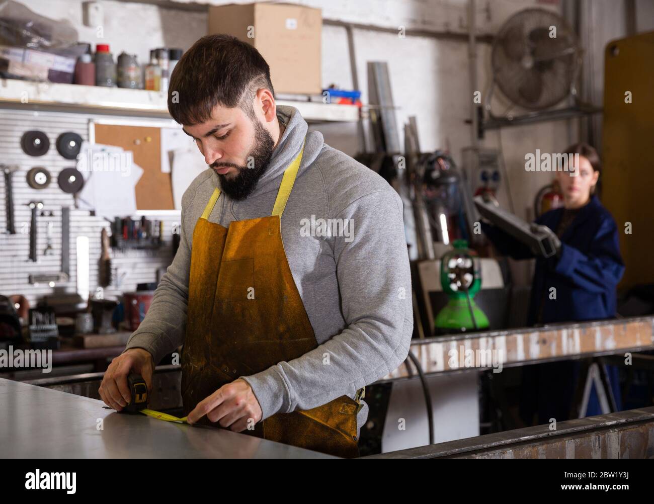 Engineer measures metal sheet with a tape measure Stock Photo - Alamy