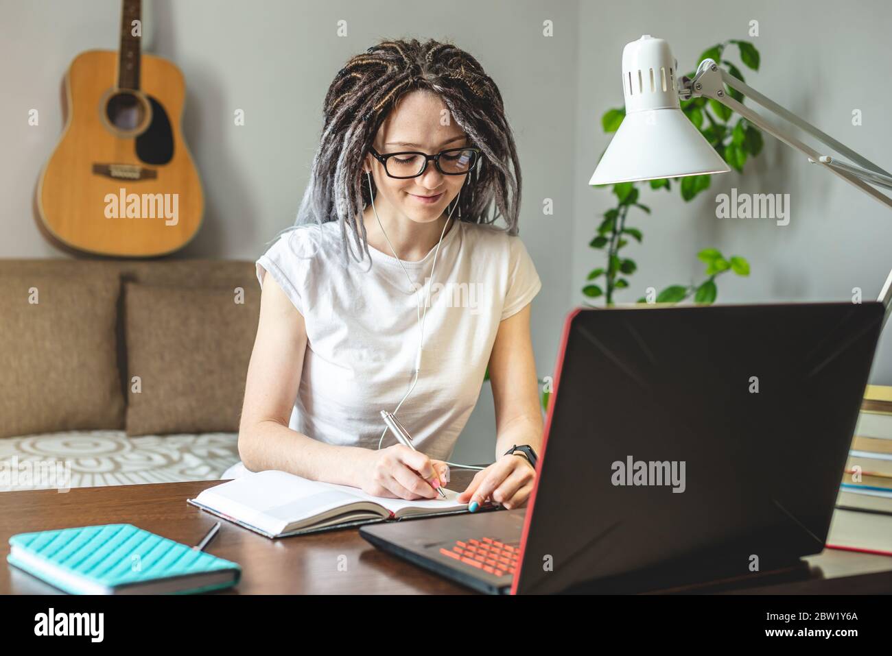 A young beautiful female student with dreadlocks is studying in an ...