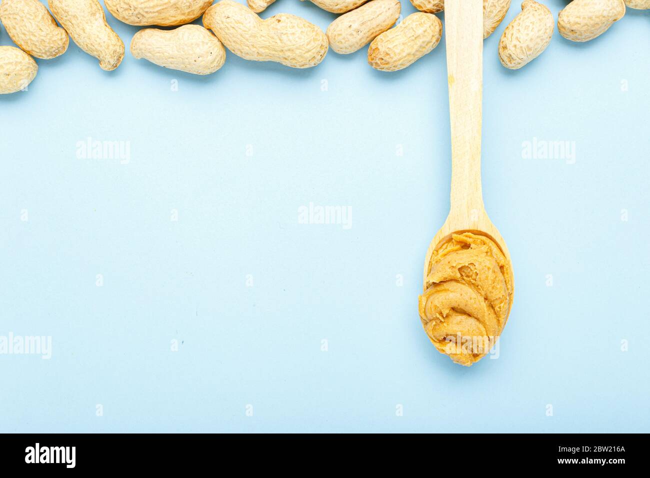 Frame made of nuts peanuts in shell and wooden spoon with creamy peanut ...