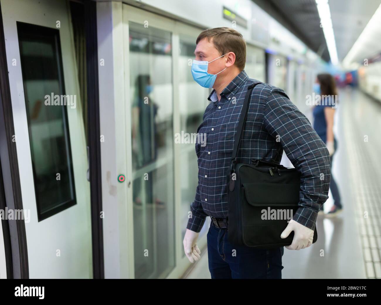 Adult man in disposable facial mask and rubber gloves landing in subway ...