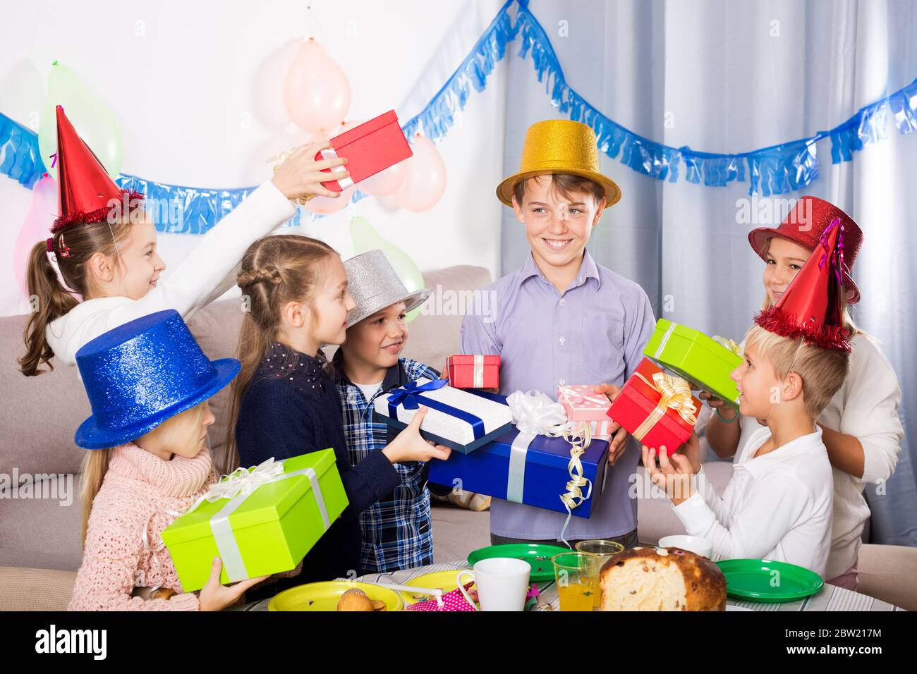Positive group of children presenting gifts to boy during birthday ...