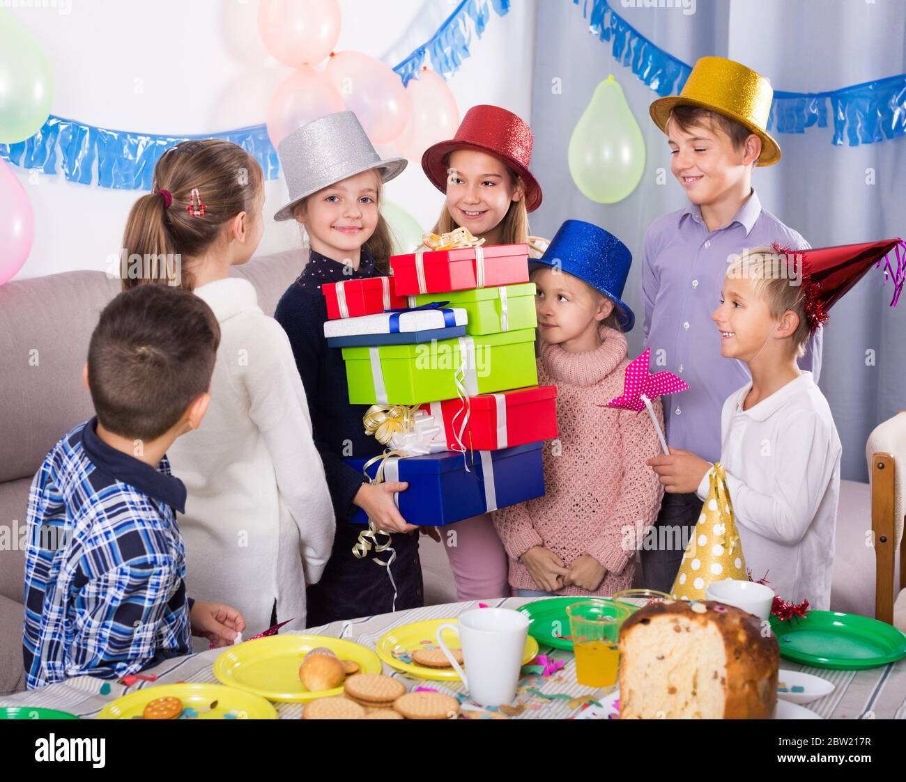 Beautiful children presenting gifts to girl during birthday party Stock ...