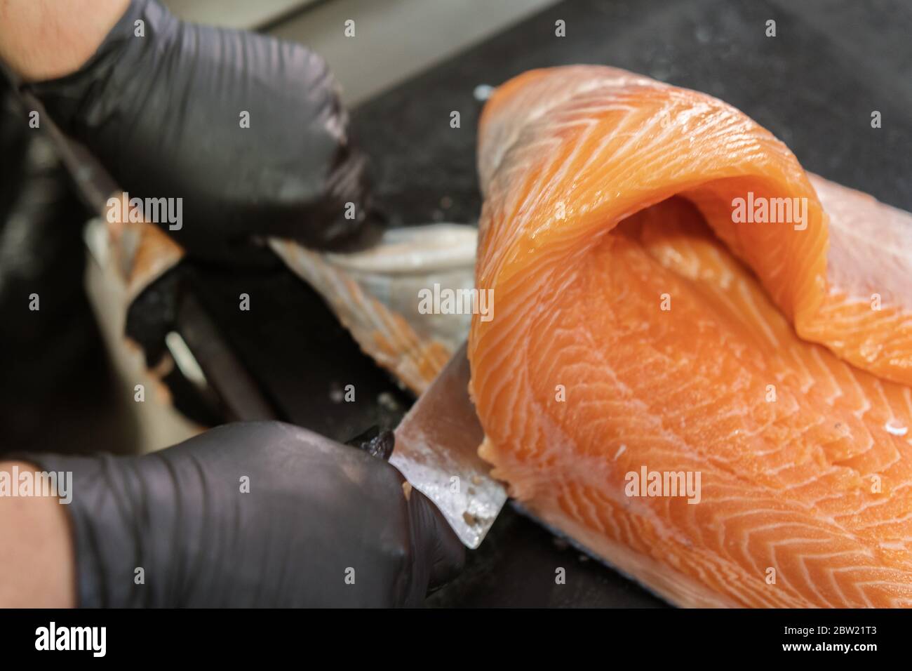 Master shusi with black hygienic gloves cleaning and preparing a huge ...