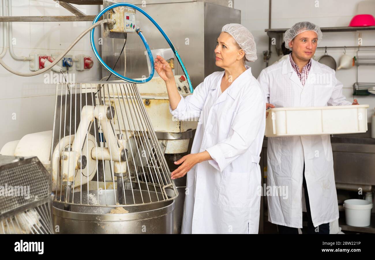 Nice bakers controlling process of making bread dough in kneading ...