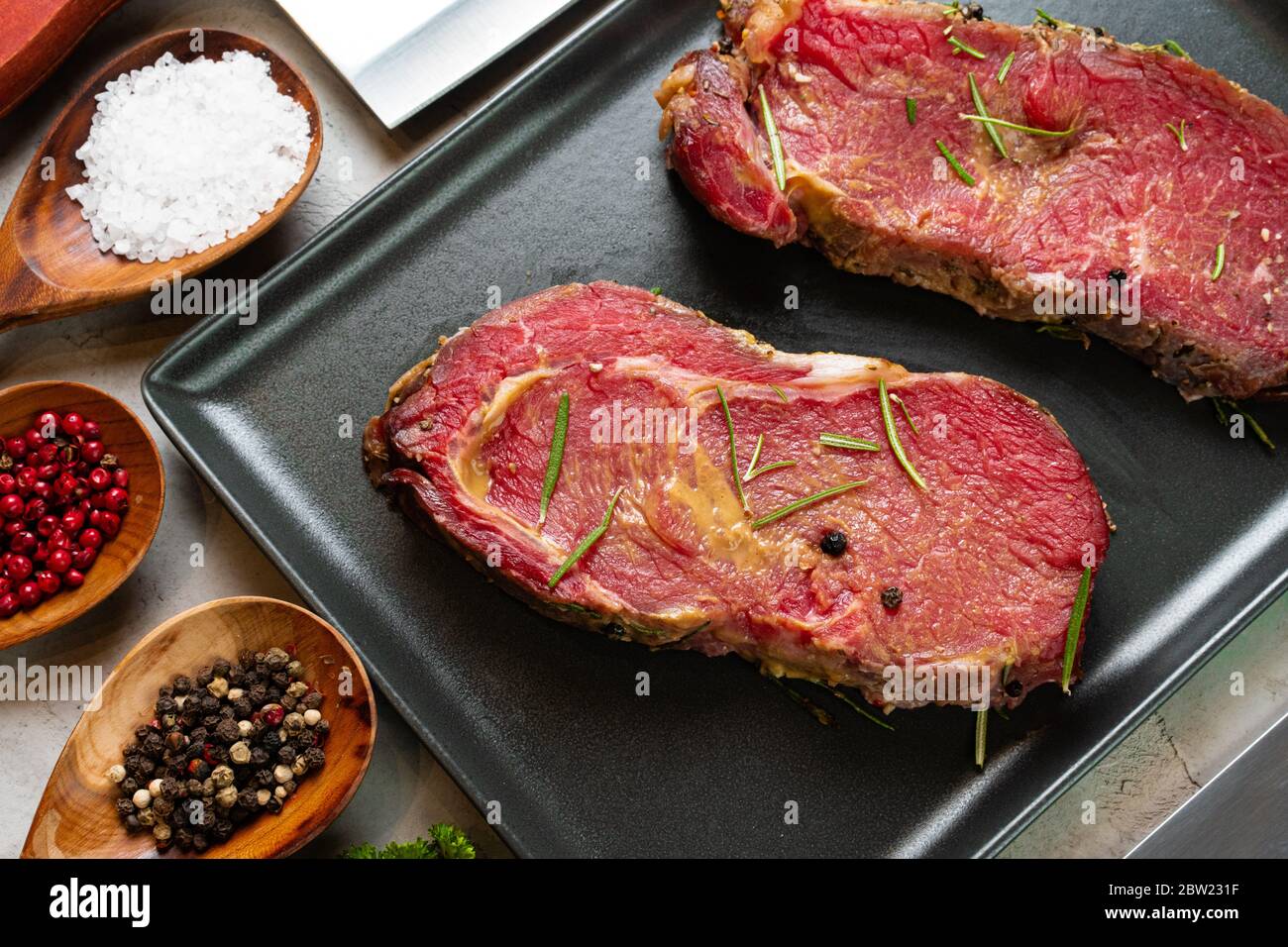 Marinated raw steaks on stone table with spices Stock Photo - Alamy
