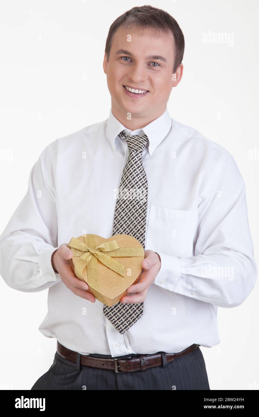 Young man with a heart shaped box in his hand on a white background ...