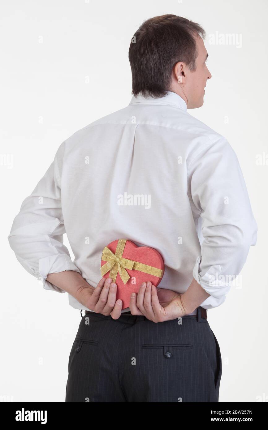 Young man with a heart shaped box in his hand on a white background ...