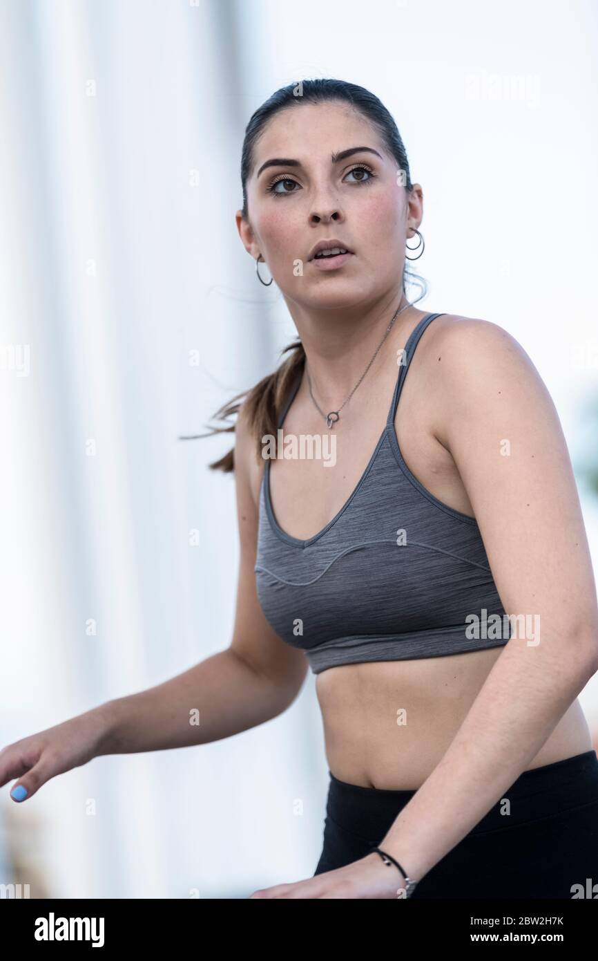 Close Up Of A Beautiful Young Woman With A Grey Sports Bra And Black Tights On An Out Of Focus close-up-of-a-beautiful-young-woman-with-a-grey-sports-bra-and-black-tights-on-an-out-of-focus
