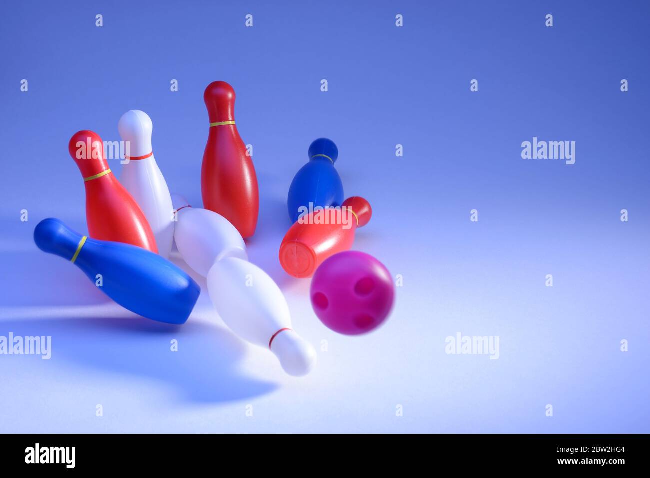 Toy plastic bowling skittles being knocked over Stock Photo - Alamy