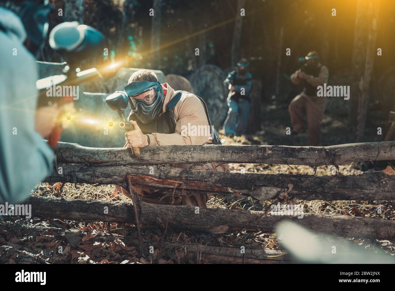 Team of male and female paintball players with marker guns aiming on ...
