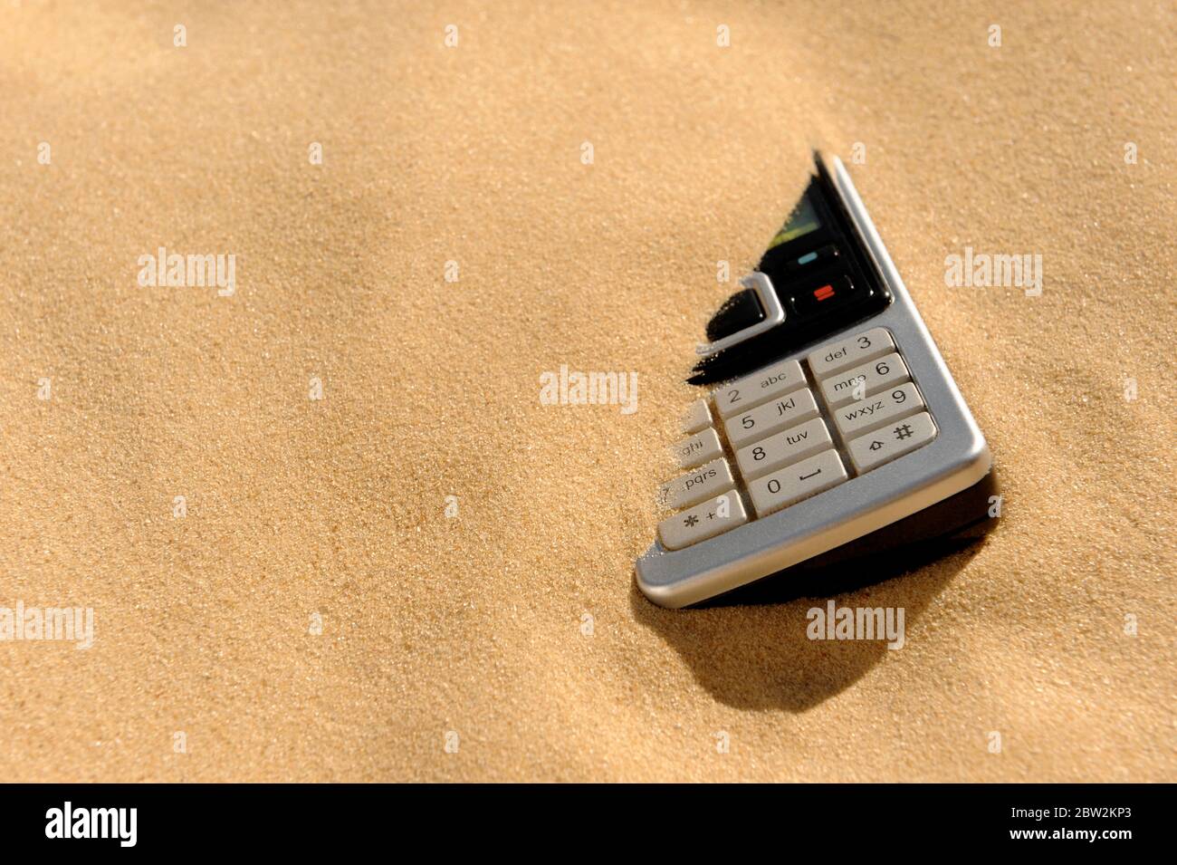 A mobile phone partially buried in sand Stock Photo - Alamy
