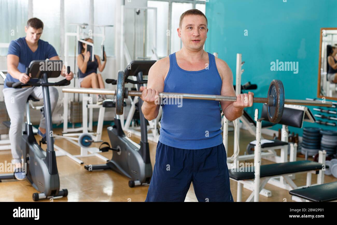 Muscular young man practicing with barbell in sport club Stock Photo ...