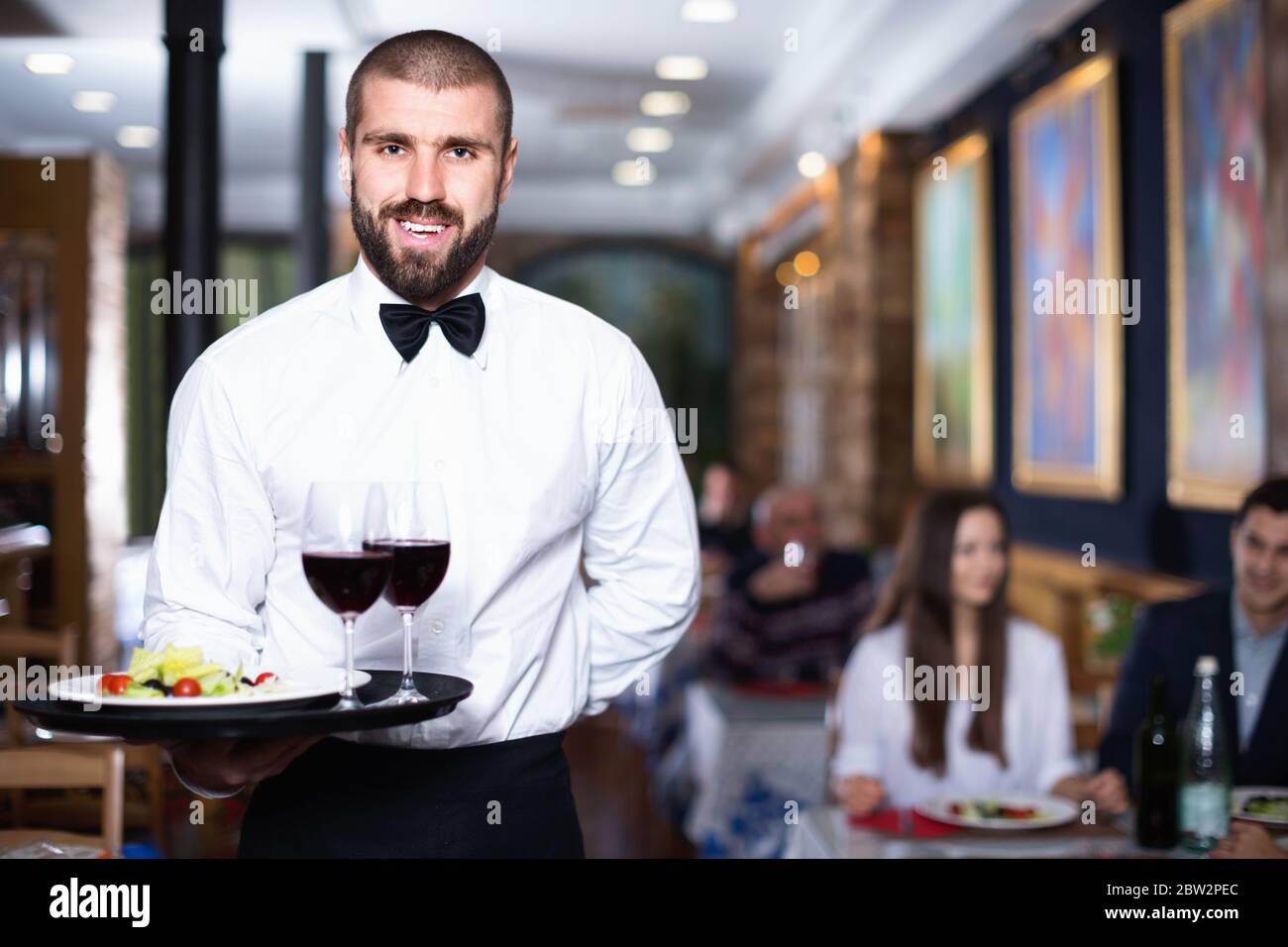 Professional friendly smiling waiter holding serving tray for ...