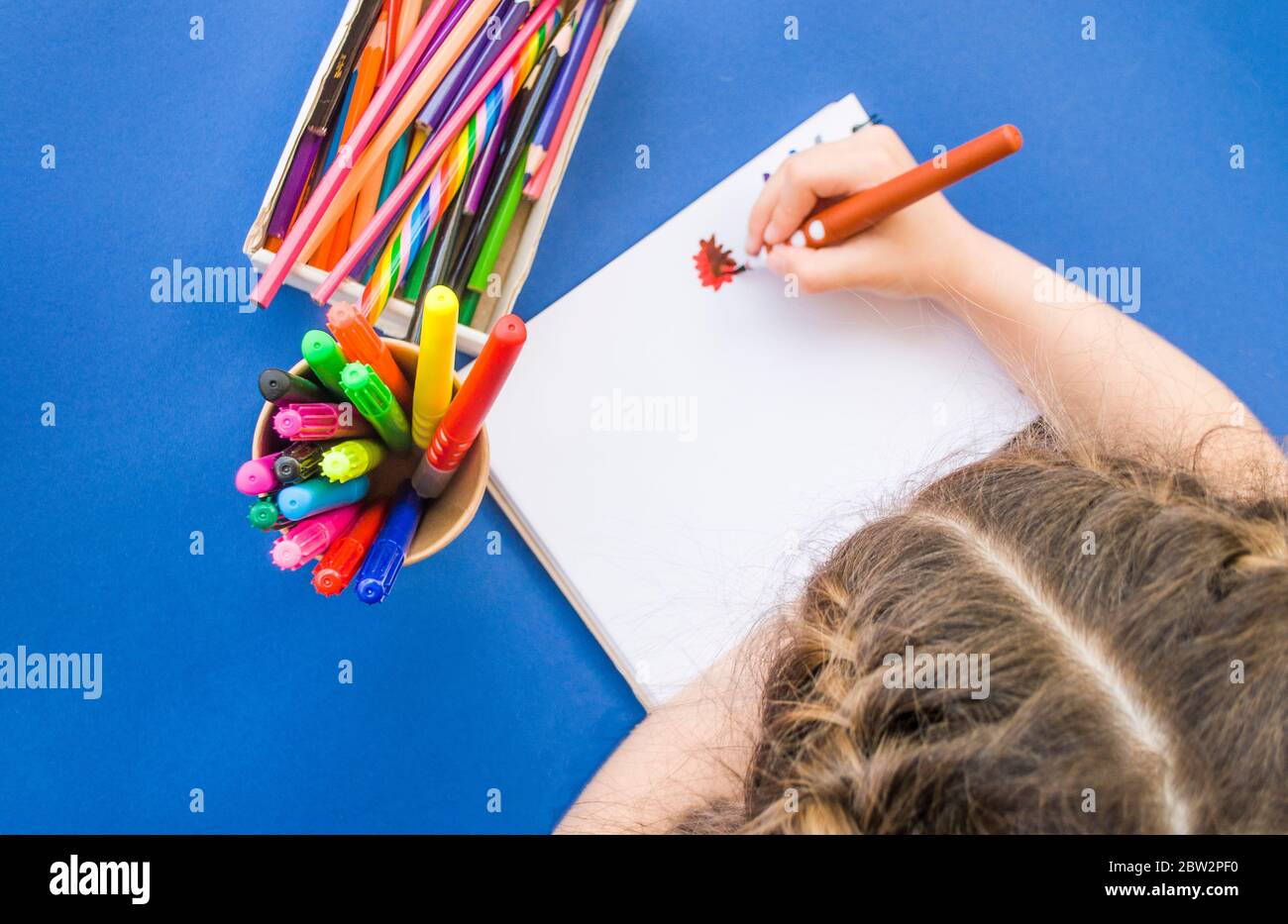 Child's drawing with colorful pencils and markers in a notebook on blue ...