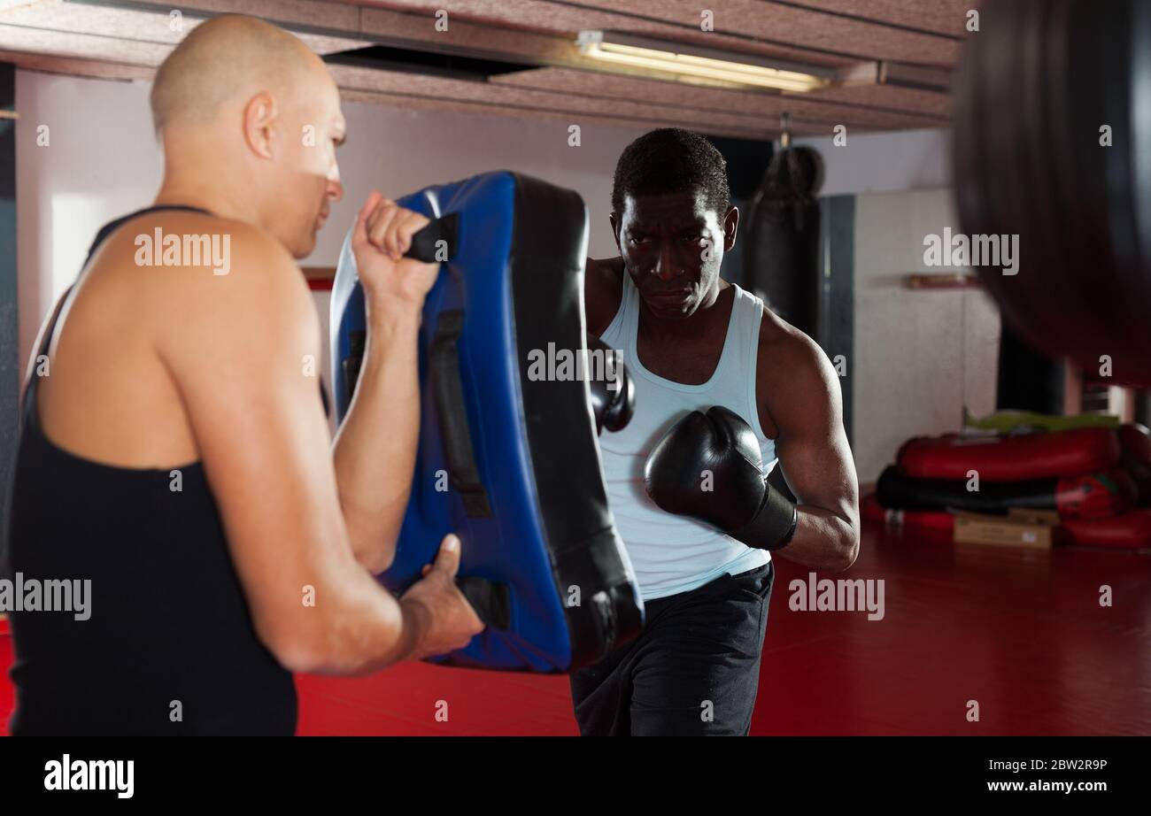 Trainer assisting african american in boxing Stock Photo - Alamy