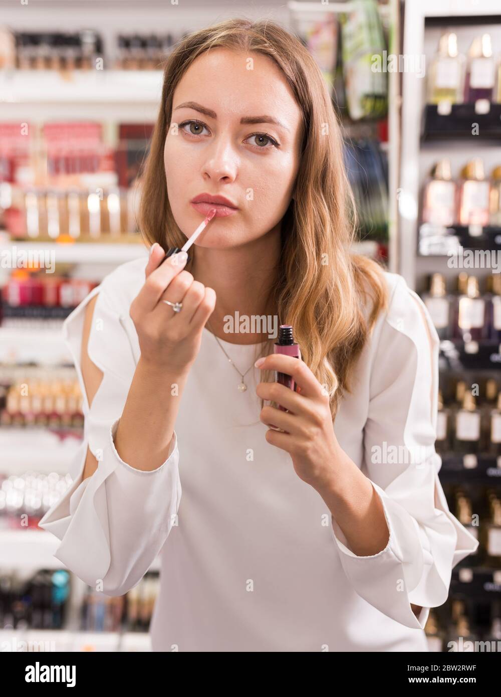 Female customer testing lip gloss in makeup store Stock Photo - Alamy
