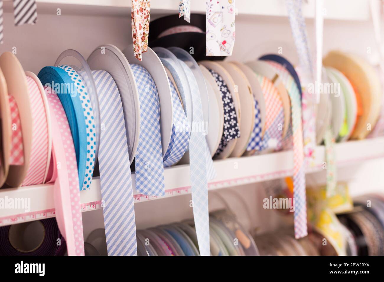 Bobbins with various colorful ribbons on counter in store. Needlework ...