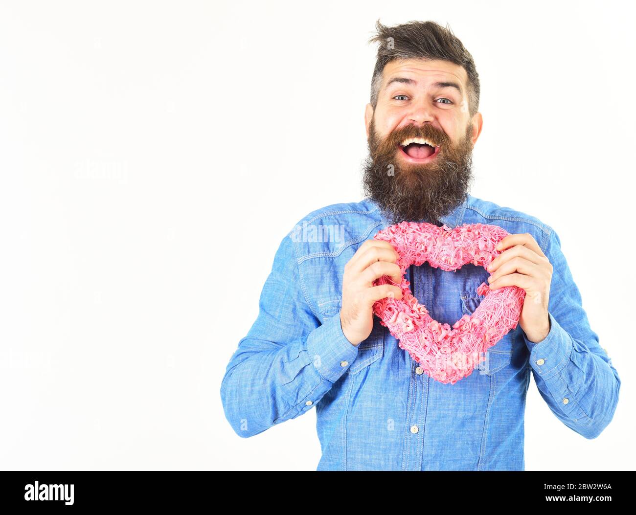 Macho with beard and romantic gift. Hipster smiles with pink heart and ...