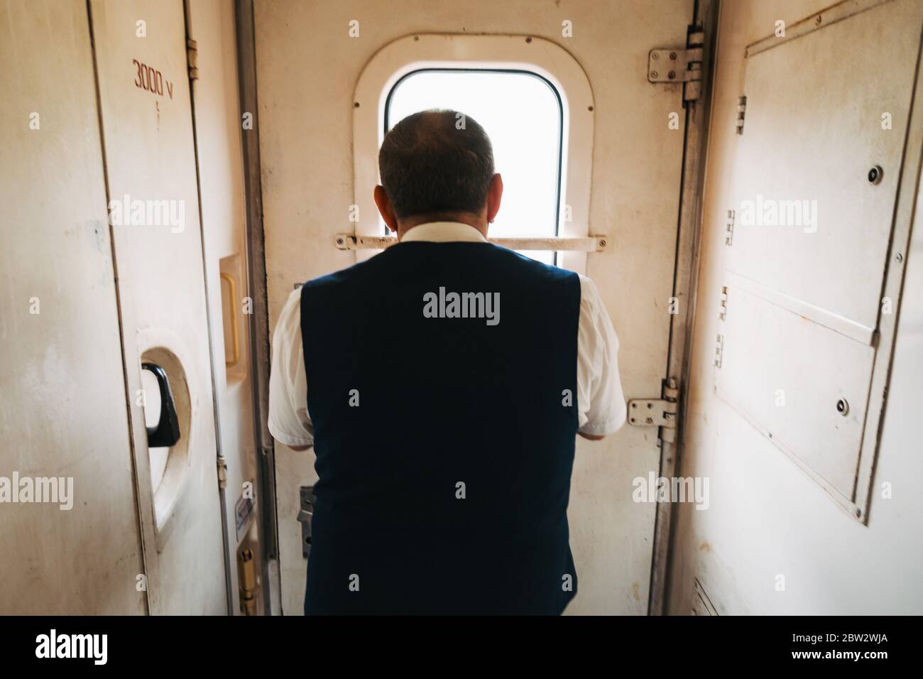 A train conductor prepares to open the door as the train nears a ...