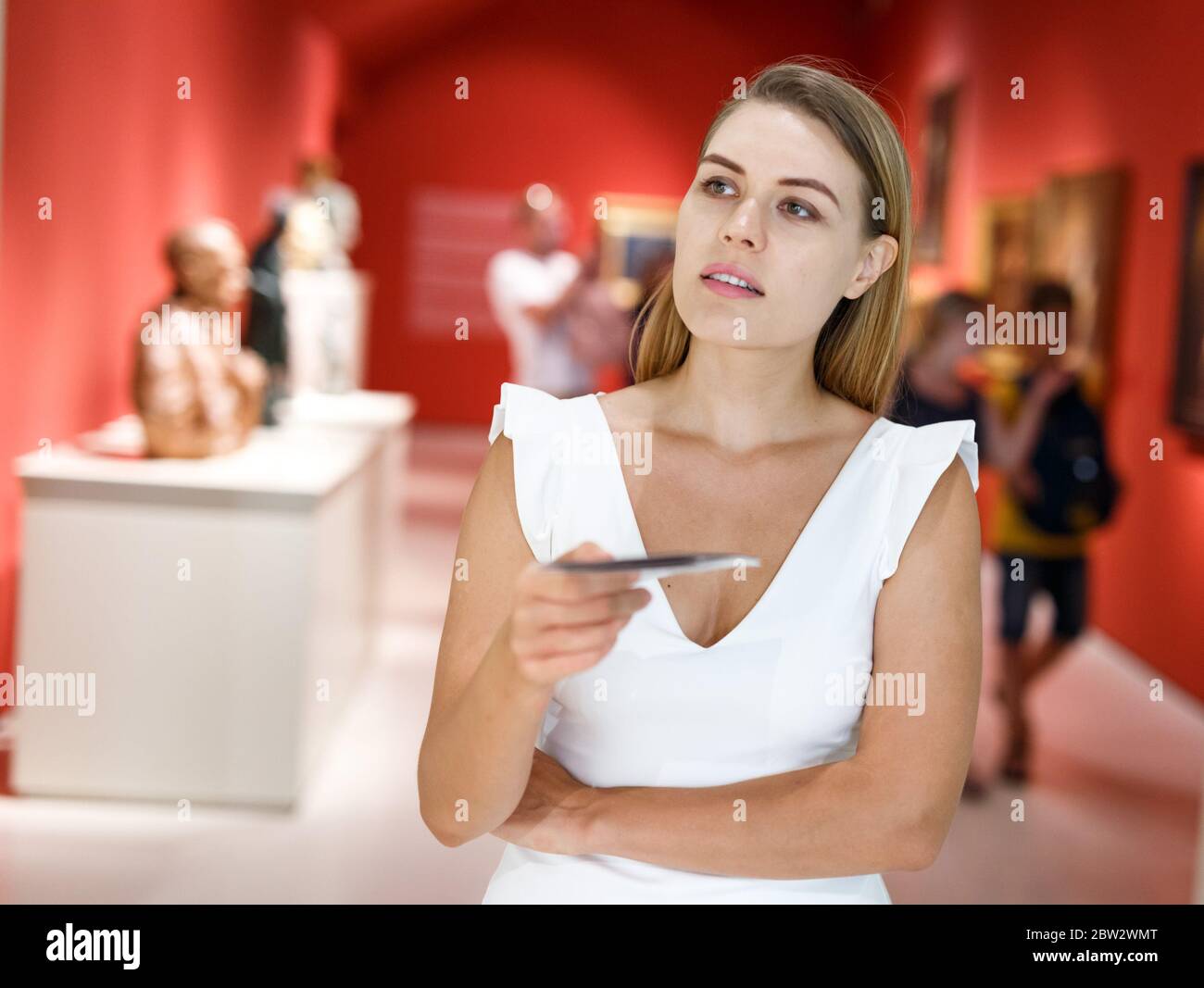 Portrait of thoughtful young woman exploring art pieces in gallery ...