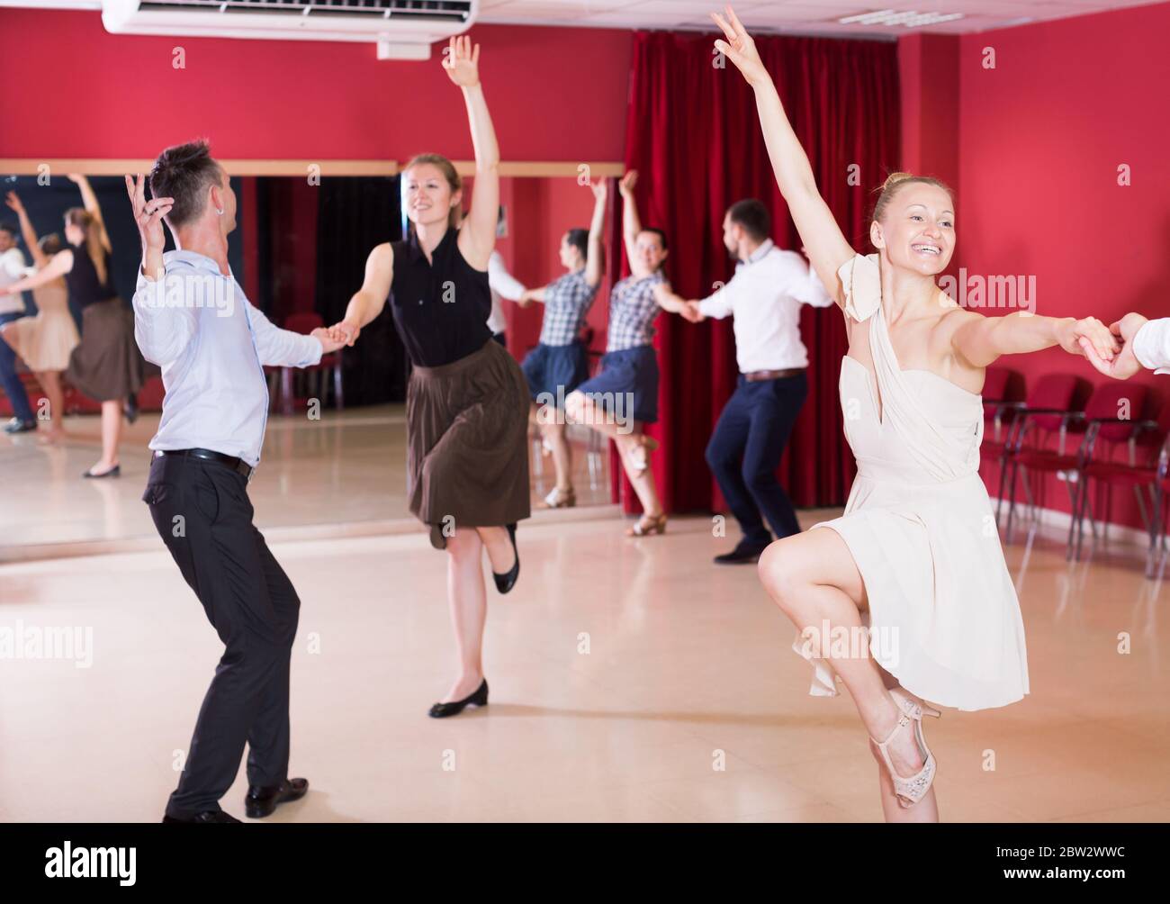 Young smiling people practicing vigorous jive movements in dance class ...