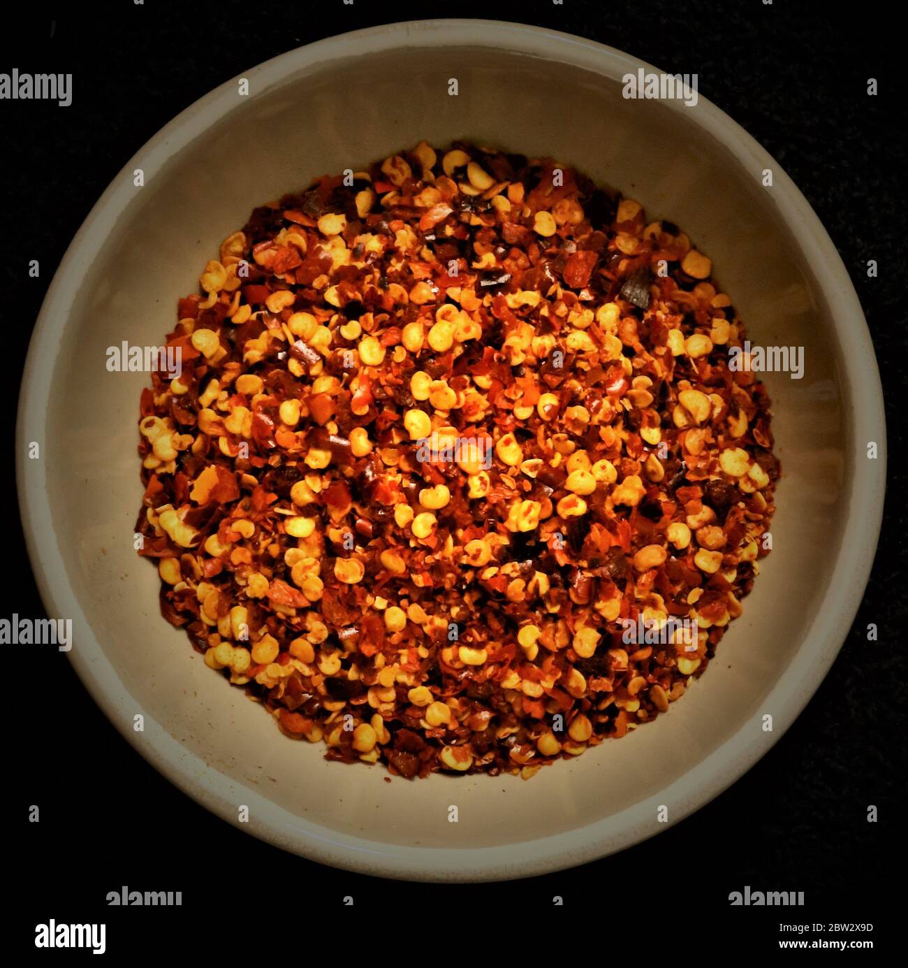 Dried chilli flakes in a small bowl Stock Photo - Alamy